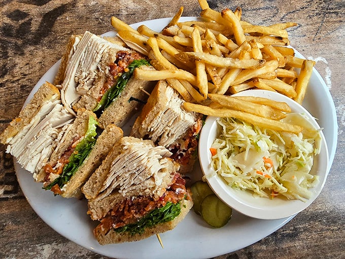 This isn't just a club sandwich&mdash;it's a three-story flavor mansion complete with crispy fries and creamy coleslaw as the landscaping.