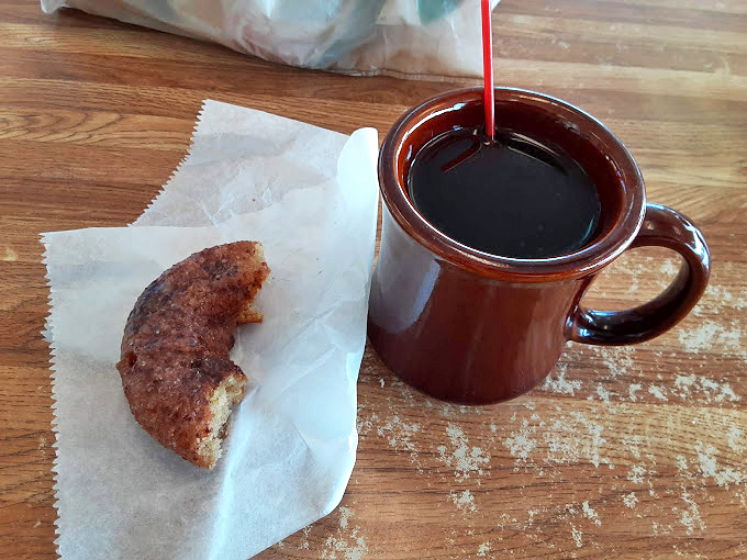 The classic pairing: strong coffee in a sturdy mug alongside a half-eaten donut &ndash; evidence of someone with proper life priorities.