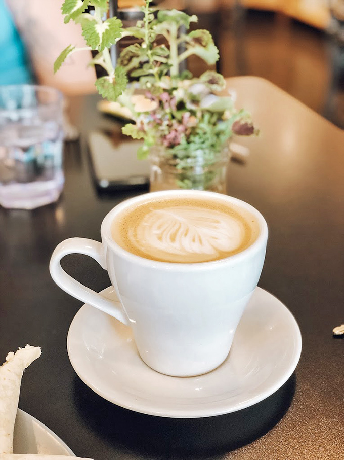 Latte art so pretty you almost don't want to drink it. Almost. The fresh herbs in the background suggest they take details seriously here.