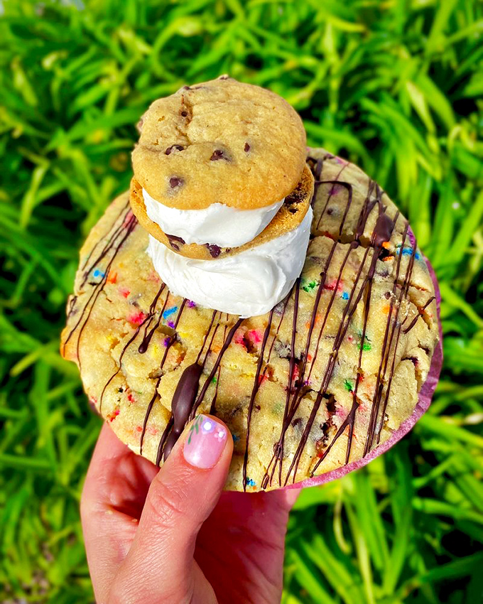 Cookie inception! A mini chocolate chip cookie riding atop its larger counterpart, drizzled with chocolate &ndash; because one cookie layer is never enough.