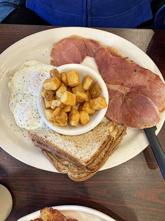 The breakfast trinity: perfectly cooked eggs, golden home fries, and country ham that didn't just phone in its smoky, savory performance.