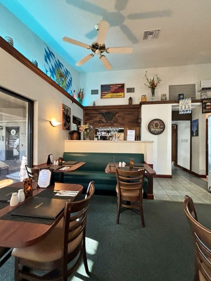 The dining area balances German tradition with Florida practicality&mdash;wood tables, teal booths, and enough ceiling fans to keep your schnitzel experience sweat-free.
