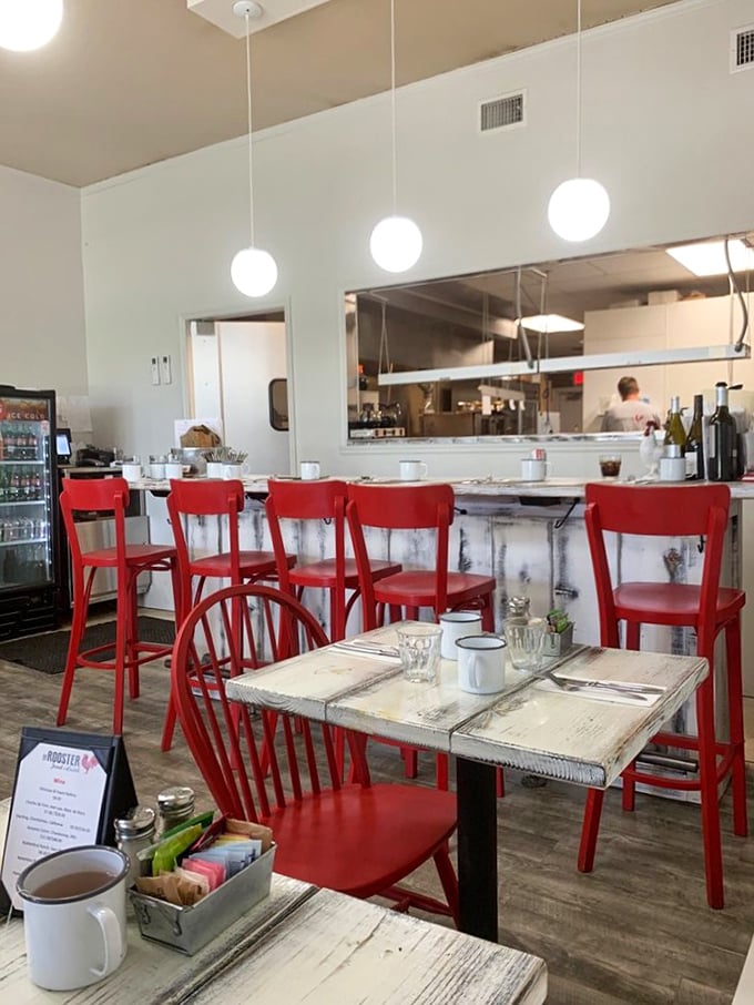 Red chairs pop against whitewashed tables while pendant lights create the perfect ambiance. The open kitchen invites you into the breakfast theater.
