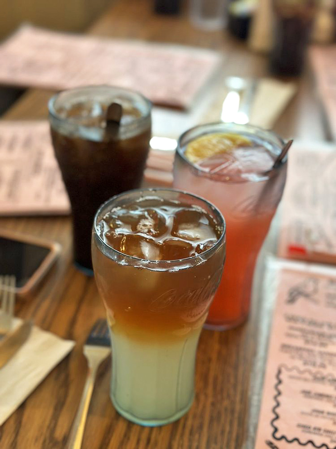The holy trinity of diner beverages: cola, root beer float, and something pink that promises to taste like childhood memories.