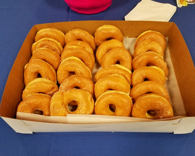 A box of glazed donuts arranged with military precision. Like soldiers of sweetness, they stand ready for their noble sacrifice.