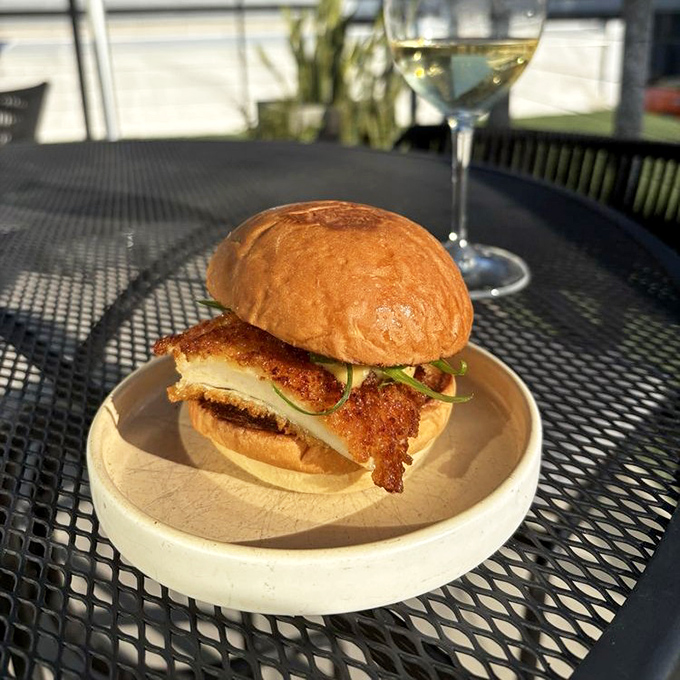 Sunshine on a plate! This perfectly crafted sandwich proves that sometimes the best dining happens outdoors, especially with a glass of white wine standing by.