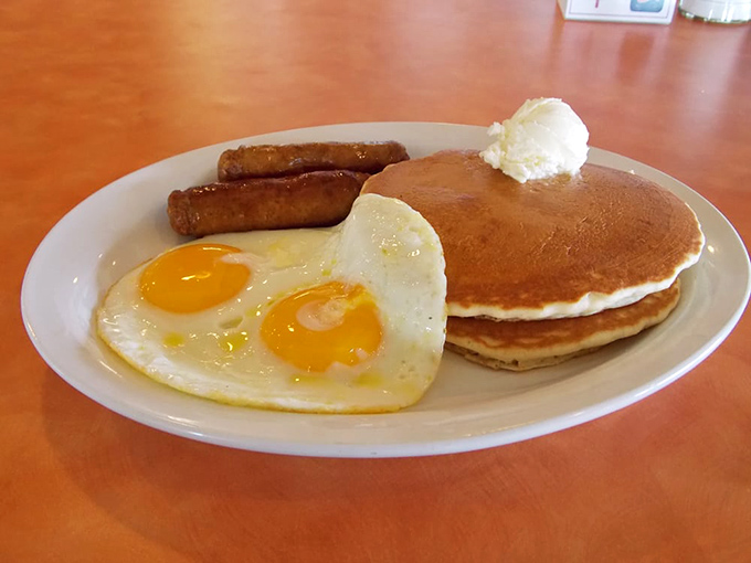 Two perfectly cooked eggs&mdash;because even breakfast deserves a little love. Served with golden pancakes and sausage links for a classic morning trio.