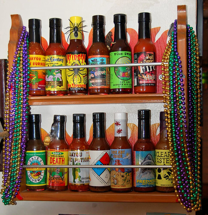 The hot sauce collection&mdash;where heat meets whimsy. Those colorful Mardi Gras beads suggest these bottles contain liquid adventures rather than mere condiments.
