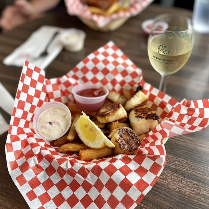 Scallops and fries nestled in their red-and-white checkered cradle, with a glass of local white standing by&mdash;a coastal California romance story in edible form.