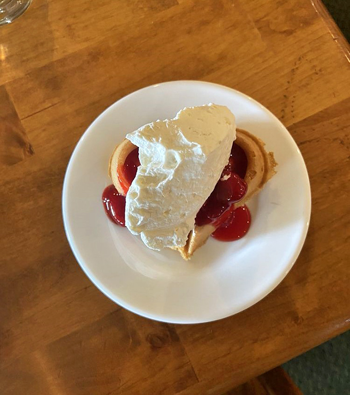 This isn't just dessert, it's architecture – a perfect waffle foundation supporting cherry pillars and a whipped cream roof that melts into sweet oblivion.