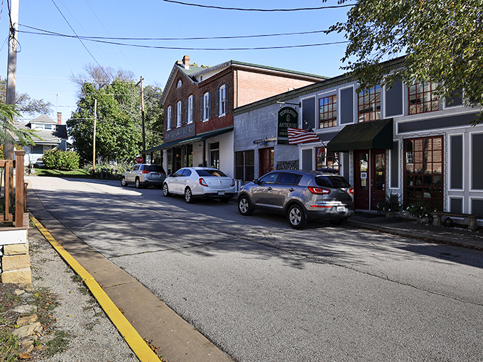 This charming street scene in Augusta, Missouri captures the town's quaint, small-town character with historic storefronts, American flags, and a peaceful, tree-lined setting.