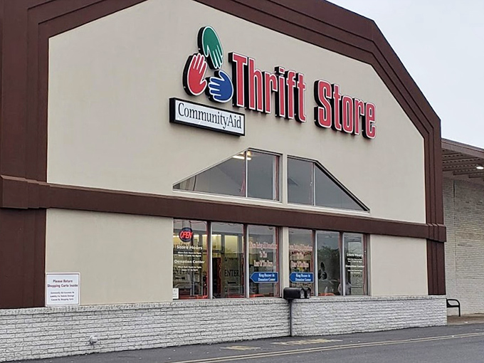 CommunityAid's distinctive brown and cream exterior stands out in the shopping center. That peaked roof hints at mountains of merchandise inside!