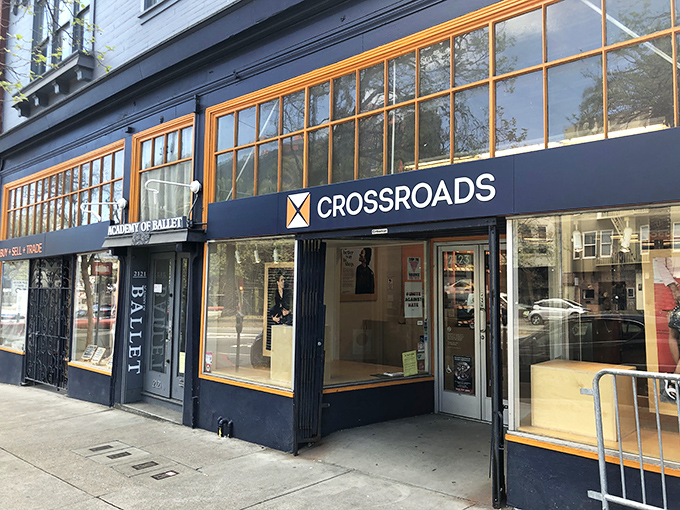 Crossroads Trading's distinctive orange-framed windows showcase fashion's second chances. Urban style meets sustainable shopping.