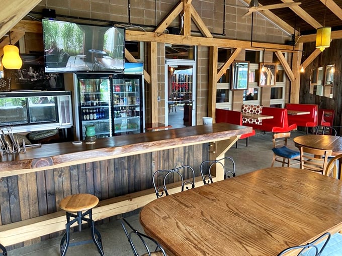 The bar area blends rustic charm with modern comfort &ndash; wooden beams overhead, live-edge bar top, and those inviting red booths calling your name.