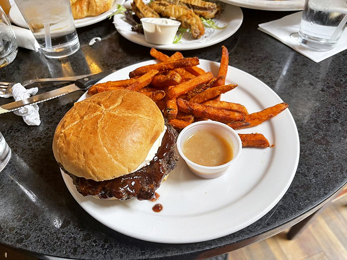A burger that requires both hands and a strategy, paired with sweet potato fries that deserve their own fan club.