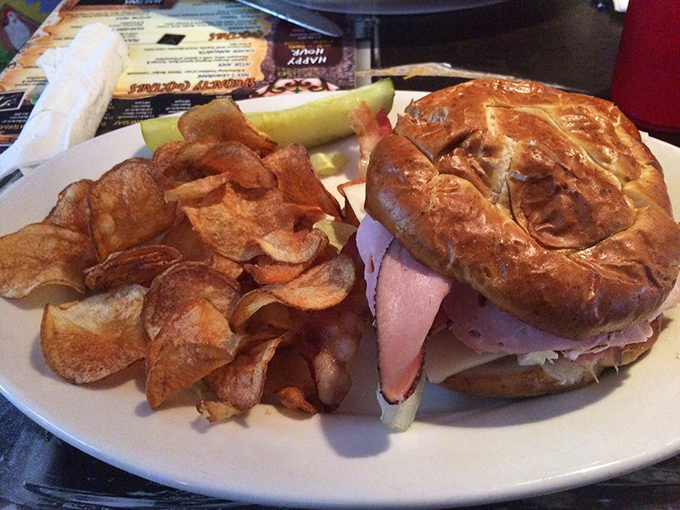 A sandwich that requires both hands and a strategy, served alongside house-made potato chips that shatter with each satisfying crunch.