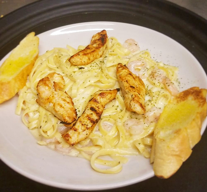Fettuccine Alfredo wearing its best accessories&mdash;perfectly grilled shrimp and garlic toast ready to soak up every last drop of that creamy sauce.