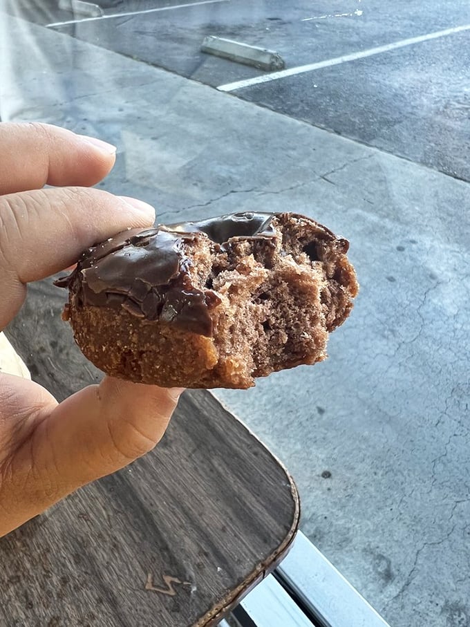 Half-eaten chocolate cake donut reveals its dense, moist interior&mdash;proof that sometimes the best food photography happens mid-bite.