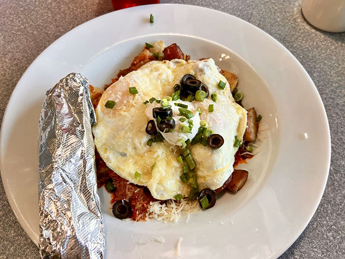 Eggs lounging atop a colorful bed of Mexican-inspired flavors. The foil-wrapped tortilla stands by, ready for its supporting role in breakfast bliss.