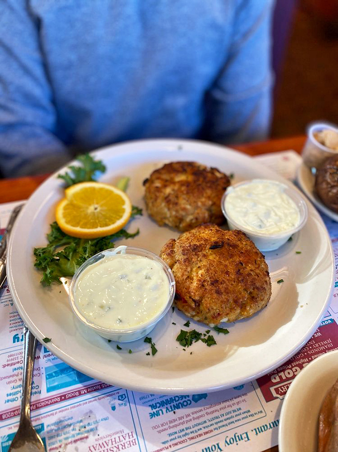 Golden crab cakes with creamy sauce showcase the kitchen's talent beyond traditional diner breakfast fare.