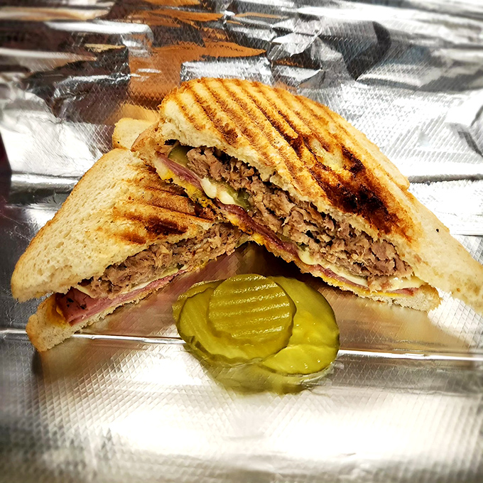 A perfectly pressed Cuban panini with pickle sidekick. The grill marks aren't just for show&mdash;they're flavor tattoos.