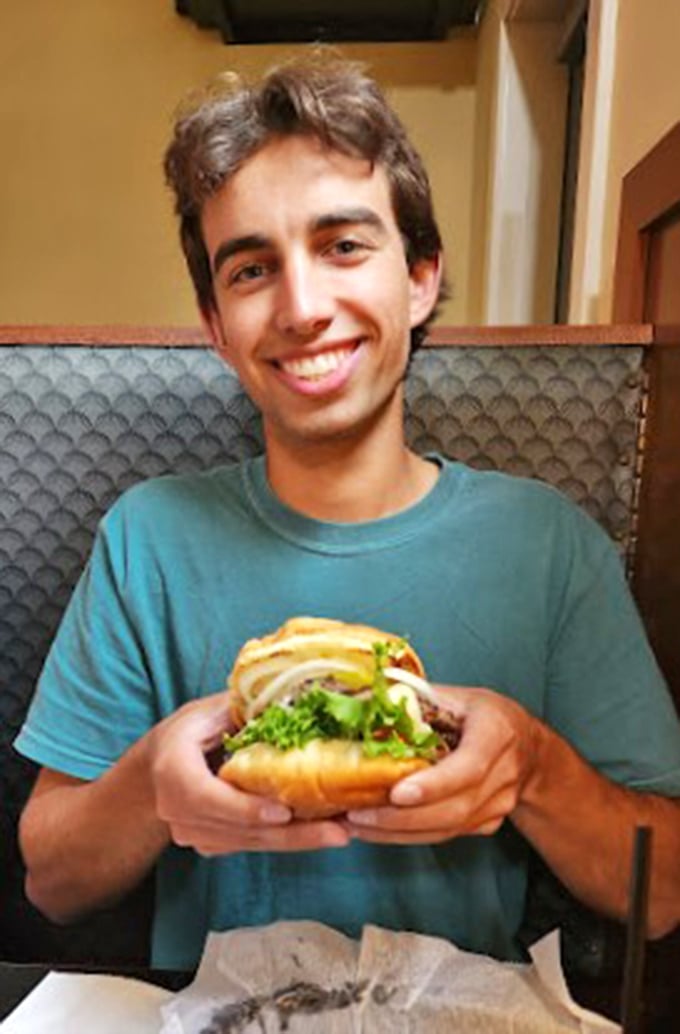 A patron enjoying what appears to be a substantial sandwich&mdash;the kind that makes conversation pause while everyone at the table admires your excellent life choices.