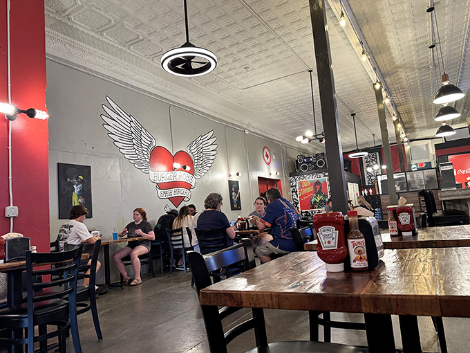 The dining room buzzes with the universal language of satisfied customers. That winged heart logo watches over the burger faithful.