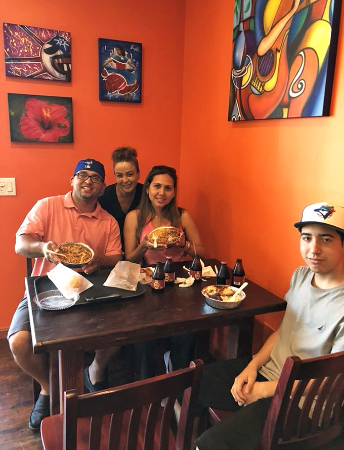 The vibrant orange walls and colorful artwork create the perfect backdrop for what really matters: faces lit up with food-induced joy.