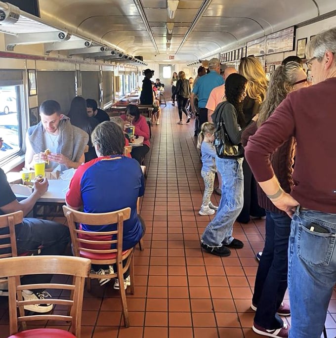 The narrow dining car creates an intimate experience where strangers become temporary neighbors united by the universal language of good food.