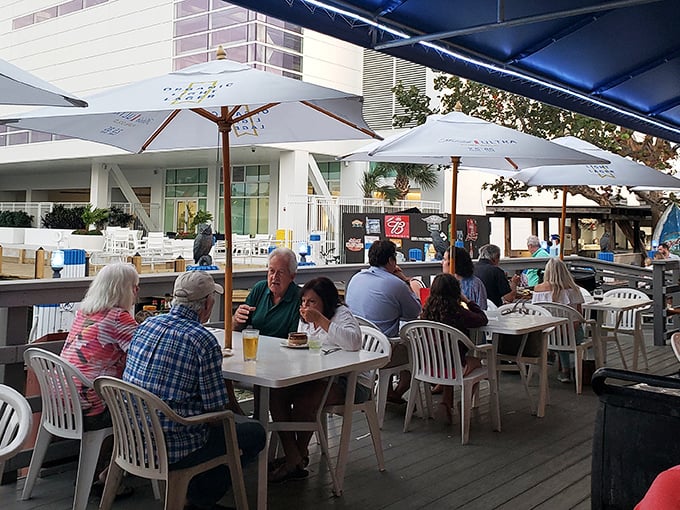 The outdoor deck where strangers become friends over cold beers and fish stories. Some tables have witnessed more laughter than comedy clubs.
