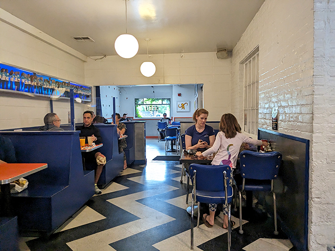 The classic black and white checkerboard floor sets the stage for a dining experience where strangers often become friends over shared tables.