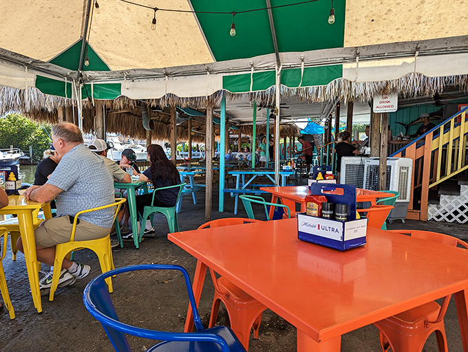 Rainbow-colored tables and chairs under a thatched roof &ndash; it's like your most relaxed self designed a dining room.
