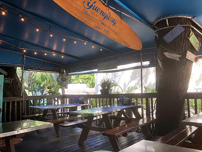String lights, surfboards, and picnic tables under a blue canopy &ndash; dining ambiance that whispers "vacation" even to locals.