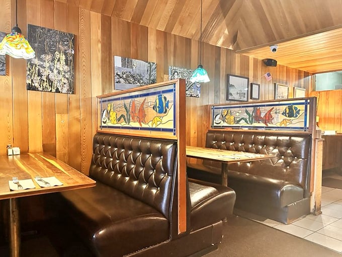 Leather booths and colorful fish-themed stained glass dividers create the perfect balance of privacy and coastal charm.