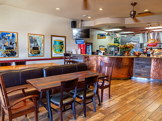 Warm wood tones and framed artwork create that "neighborhood favorite" atmosphere. The copper-fronted counter hints at the kettle-cooking magic happening just beyond.