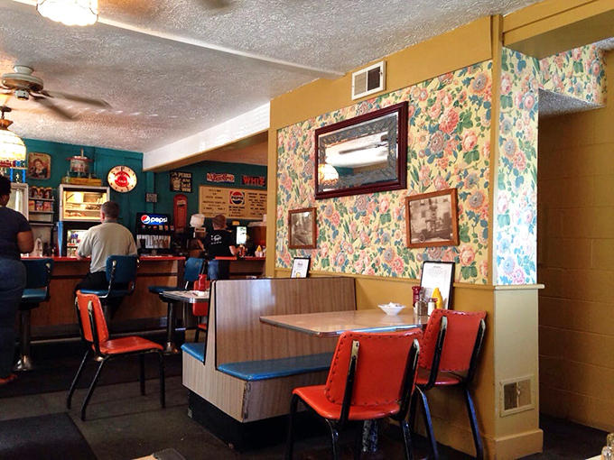 Classic diner booths where countless life decisions have been made over coffee. The floral wallpaper has witnessed more heartfelt conversations than most therapists. 
