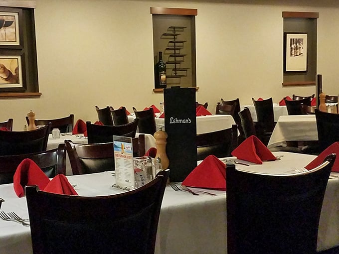 Tables set with military precision, each red napkin standing at attention. The dining room waits expectantly, like a theater before the show begins.