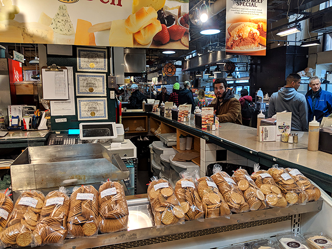 The communal seating area where strangers become temporary friends, united by powdered sugar mustaches and shared donut euphoria.