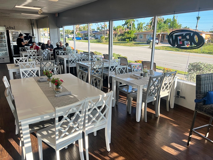 The bright, airy dining area invites lingering conversations over coffee and pastries, where Florida sunshine streams through windows onto pristine white tables.