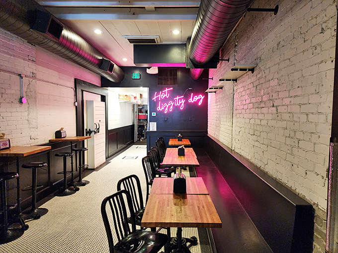 Industrial-chic meets comfort in this dining area, where pink neon proclaims "Hot diggity dog" against exposed brick walls.