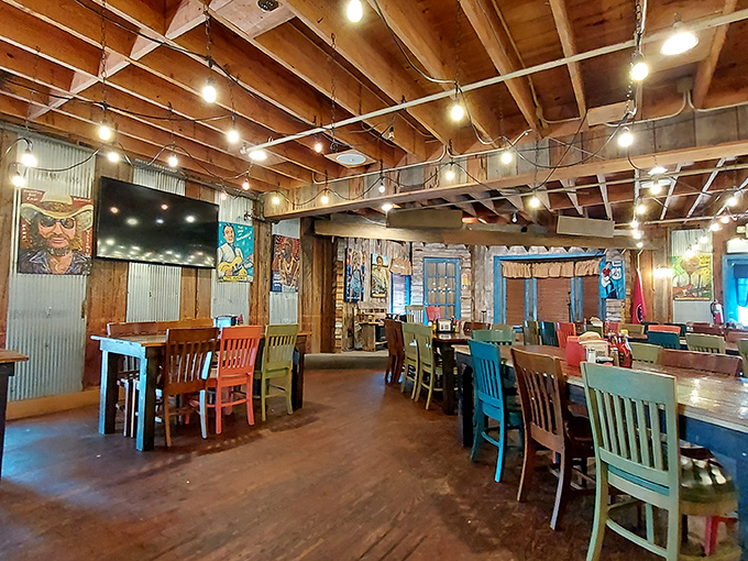Colorful mismatched chairs add whimsy to the rustic dining space, where exposed beams and string lights create a homey, unpretentious atmosphere.