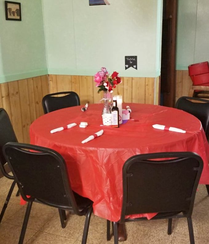 A table set with simple red tablecloth and fresh flowers&mdash;proof that hospitality doesn't need fancy linens, just genuine warmth and clean silverware.