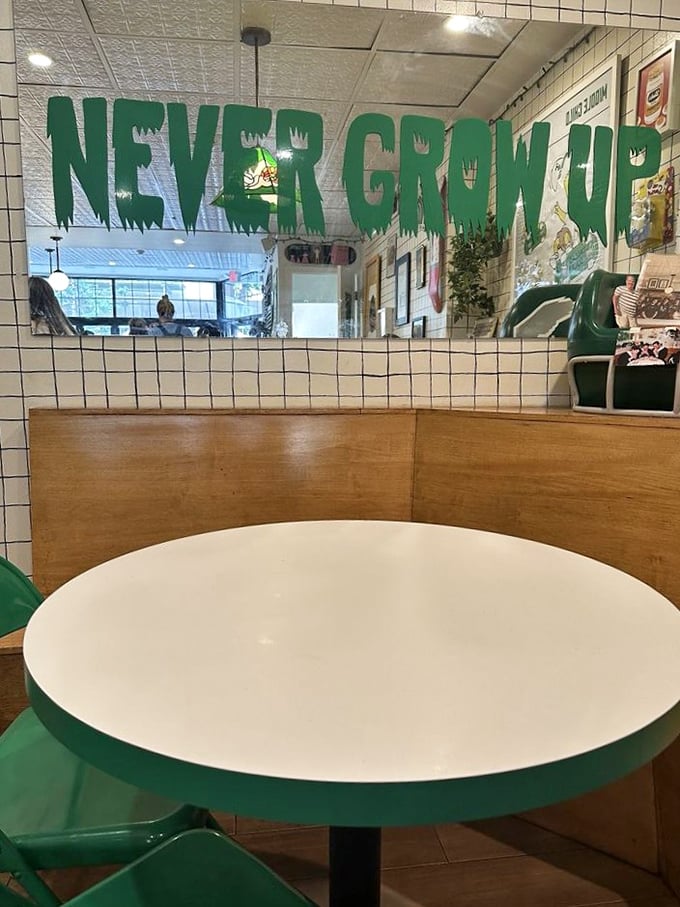 "Never Grow Up" proclaims the mirror, while the minimalist white tables with green trim say, "But we take our food seriously."