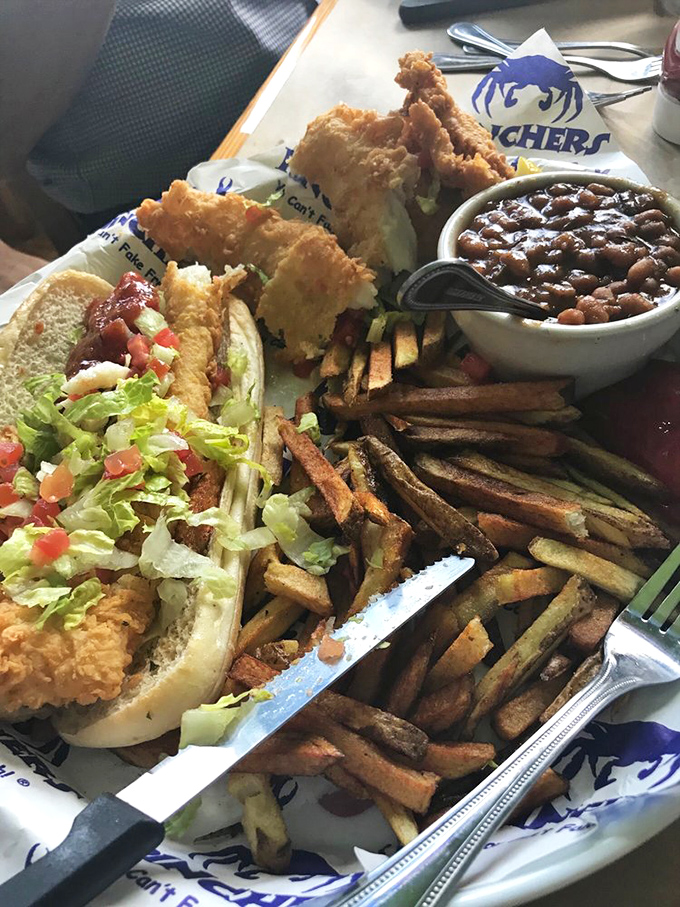 The ultimate seafood sandwich experience: golden-fried fish spilling out of its bun, with fries and beans playing delicious supporting roles.