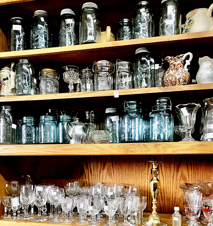 The light playing through vintage Mason jars creates a blue symphony. Before plastic took over, these sturdy vessels preserved summer's bounty.