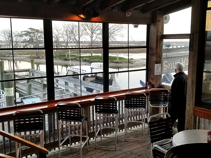 Windows framing the marsh views like living paintings—nature's dinner theater where boats and birds provide the entertainment.