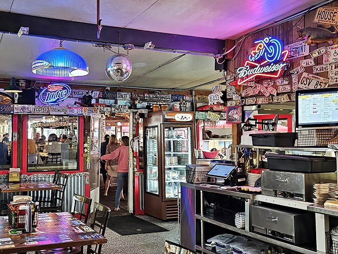 The dining room buzzes with conversation while neon signs cast a warm glow over satisfied customers.