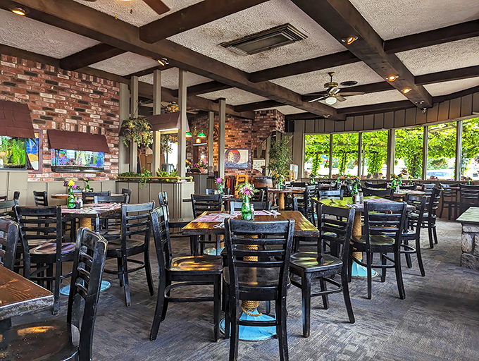Sunlight streams through windows framing lush greenery outside, making this dining room feel like a secret garden with table service.