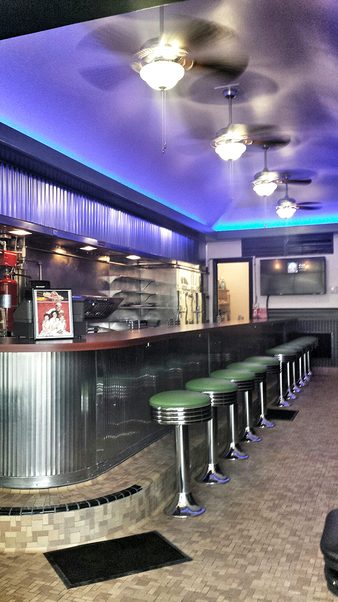 Counter seating illuminated by blue accent lighting&mdash;where solo diners become regulars and the breakfast magic happens mere feet from your hungry eyes.