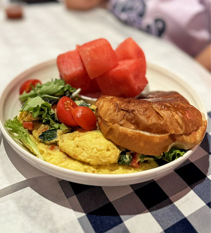 A fluffy omelet shares the plate with fresh tomatoes and a buttery croissant. Breakfast doesn't get more photogenic than this, folks.